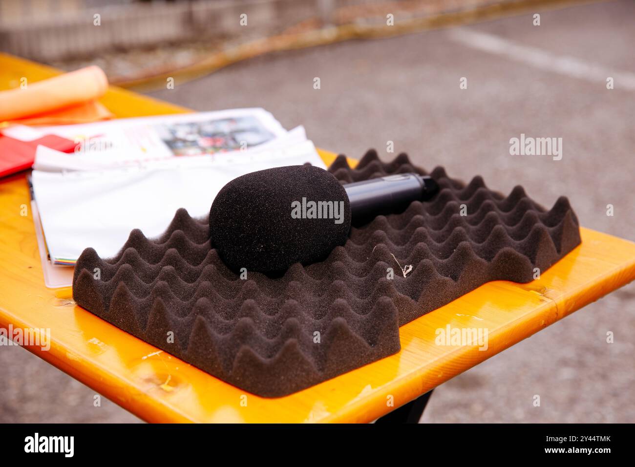 Microphone sitting on soundproof foam, an outdoor table setup shows ...