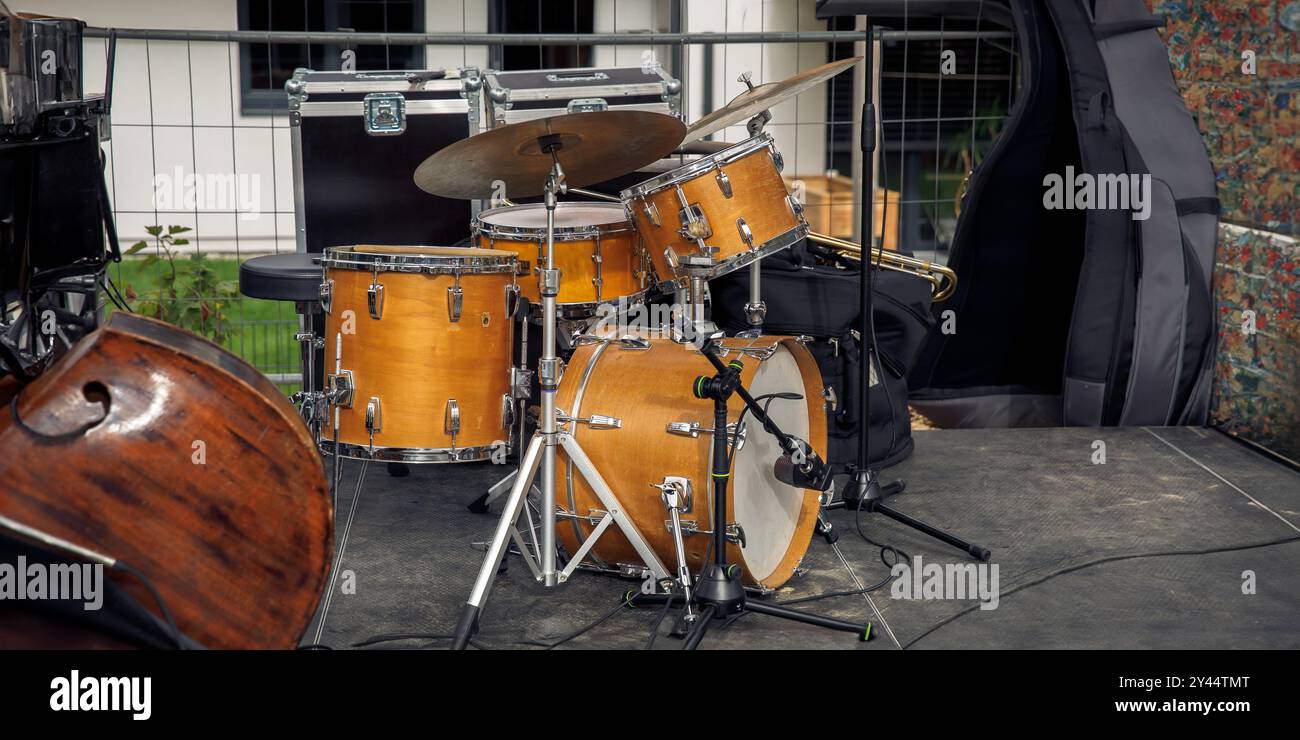 On an outdoor stage, a drum set with closed double bass case, musical ...