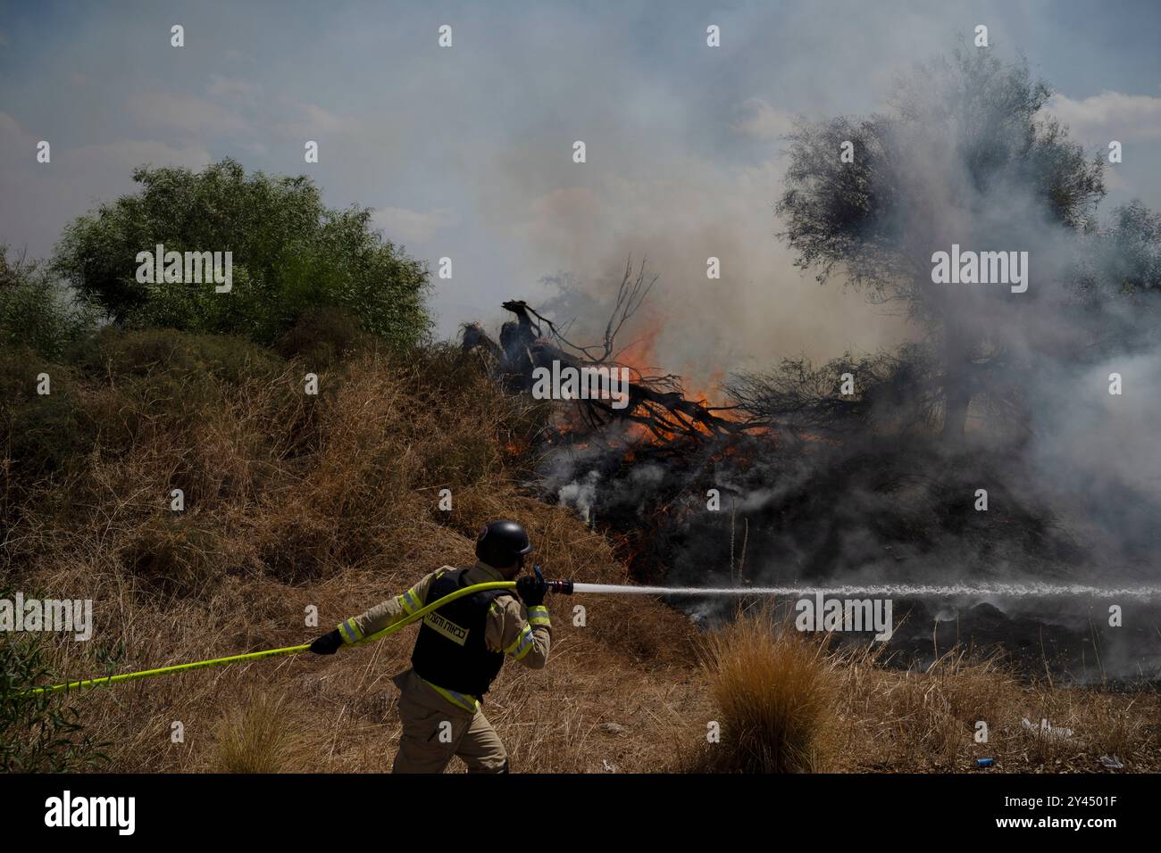 An Israeli firefighter works to extinguish a fire burning in an area ...