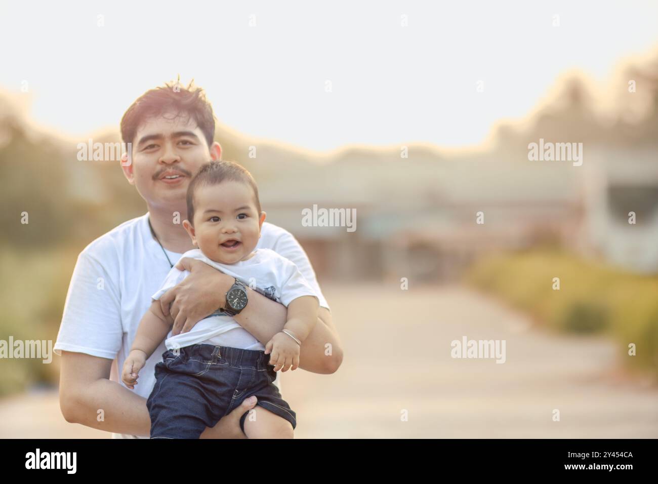 a father holding his baby boy faces the camera with a smile. father and ...