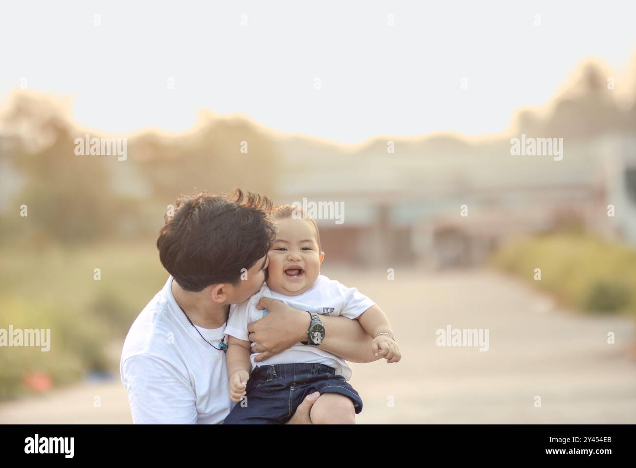 a father holding and kissing his baby boy. father and baby boy look ...