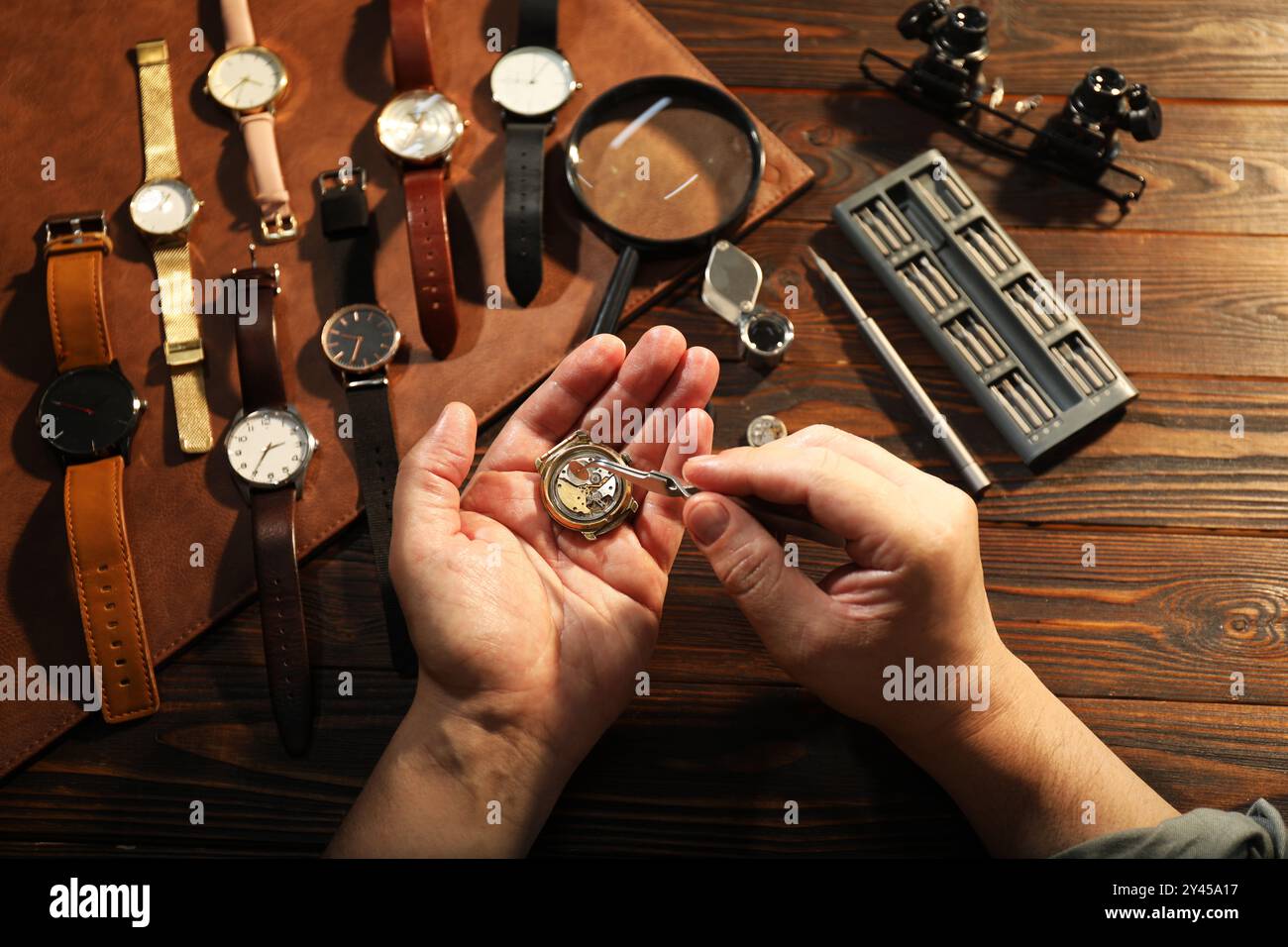 Man fixing mechanism of vintage wrist watch at wooden table, top view ...