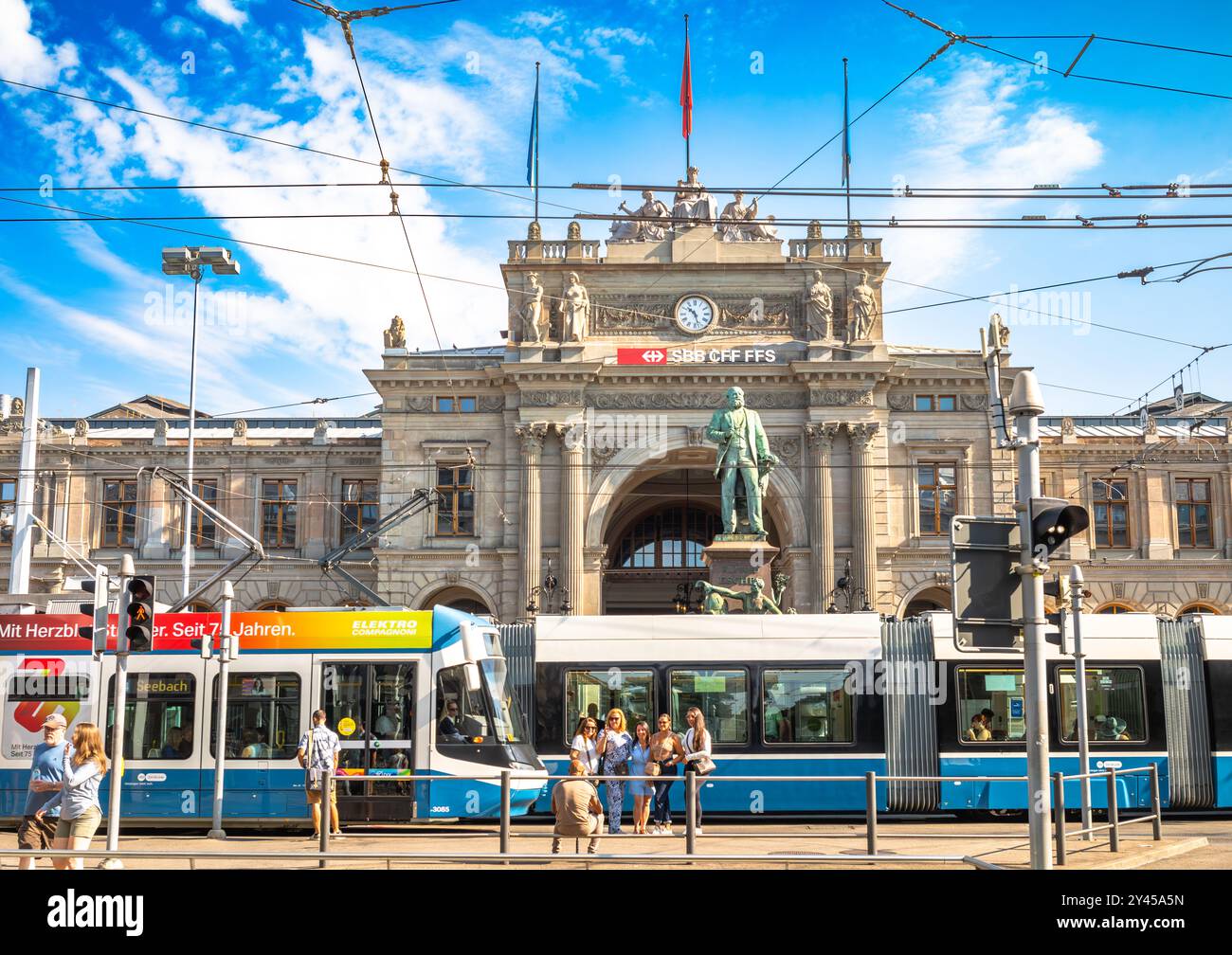 Two trams pass next to the statue of Alfred Escher, the Railroad King ...