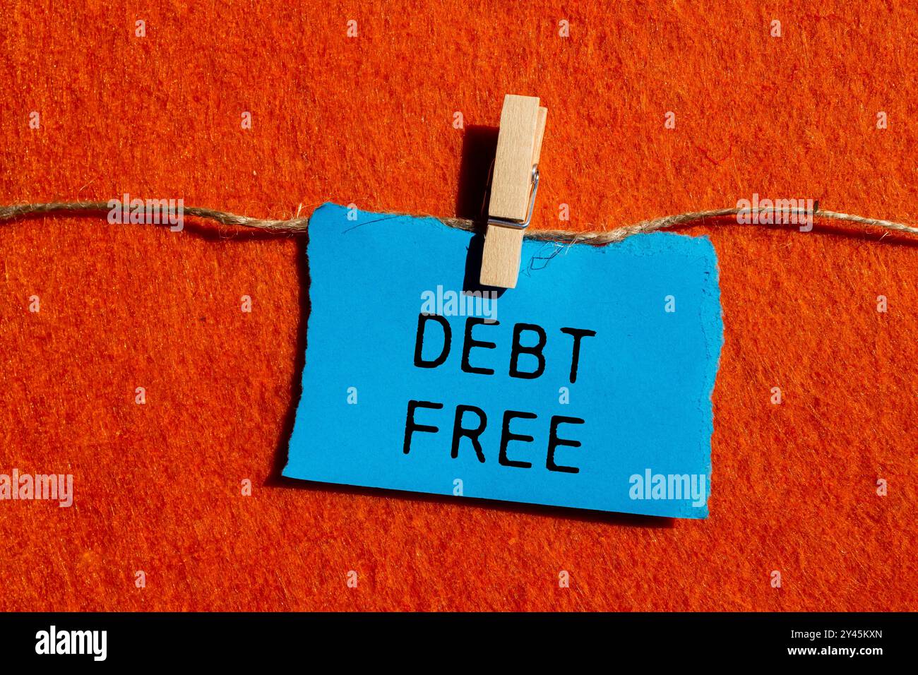 Debt free message written on ripped blue torn paper piece on orange ...