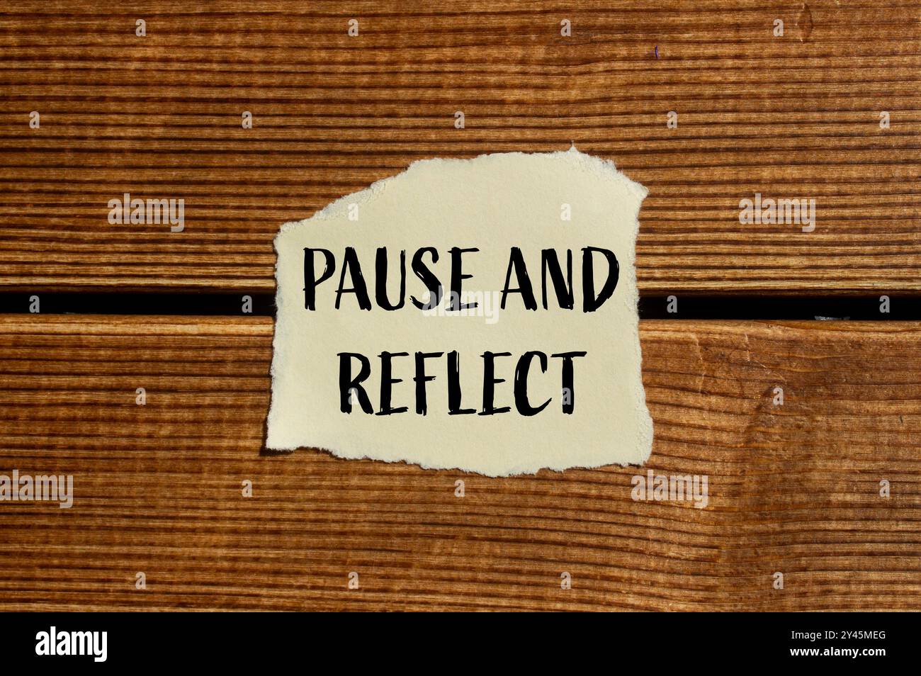 Pause and reflect message written on ripped torn paper with wooden ...