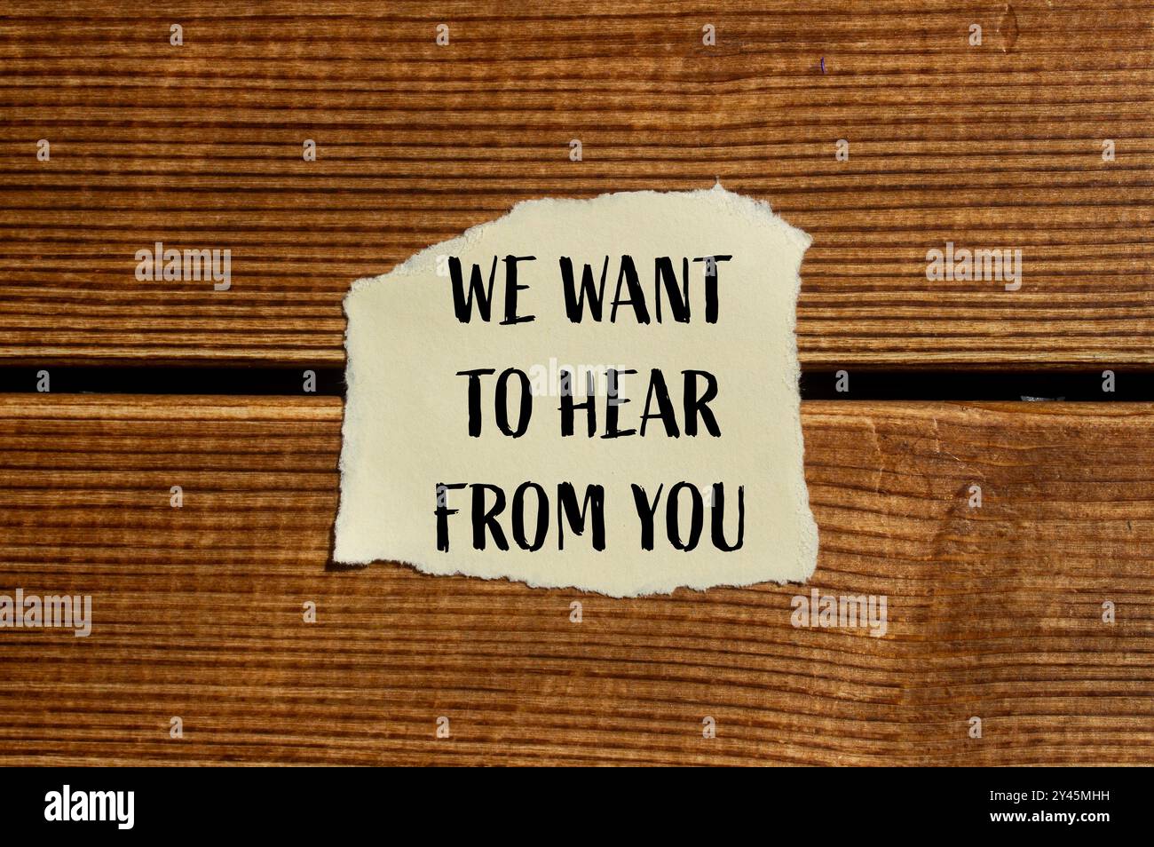 We want to hear from you message written on ripped torn paper with wooden background. Conceptual ...
