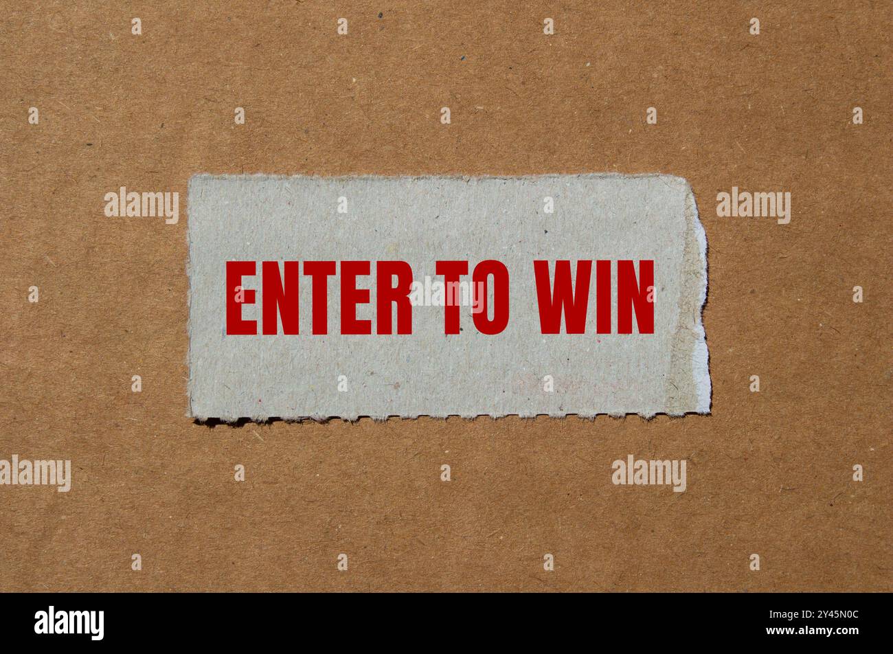 Enter to win message written on ripped torn paper piece with cardboard ...