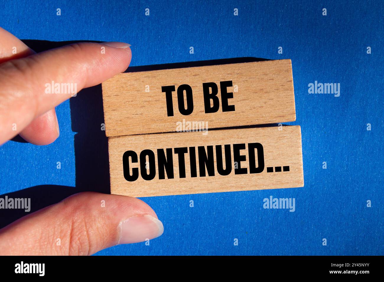 To be continued message written on wooden blocks with blue background ...