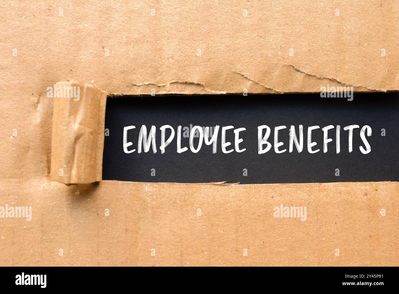 Employee benefits message written on ripped torn cardboard paper with black background ...