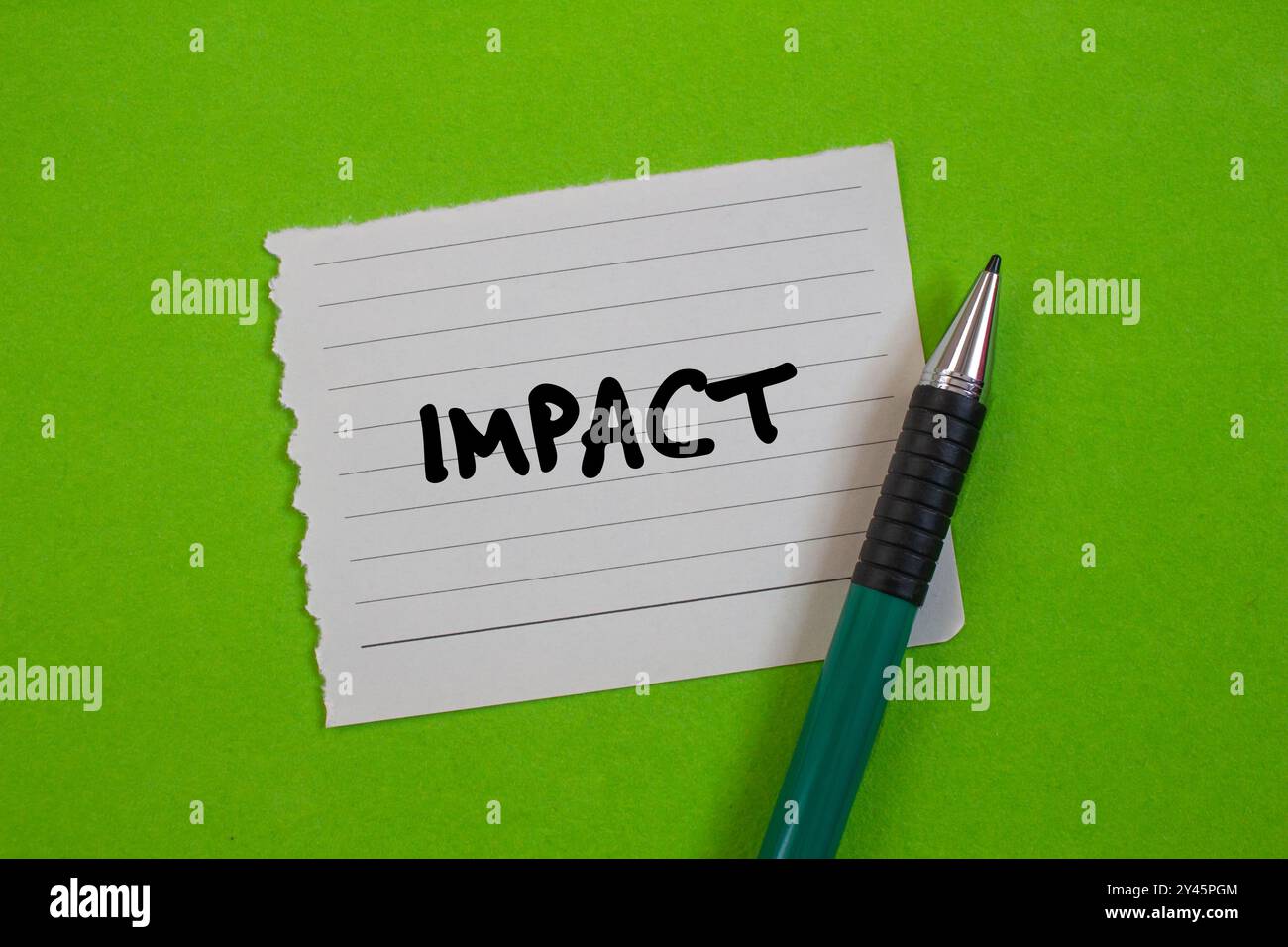 Impact word written on ripped torn paper with a pen on green background ...