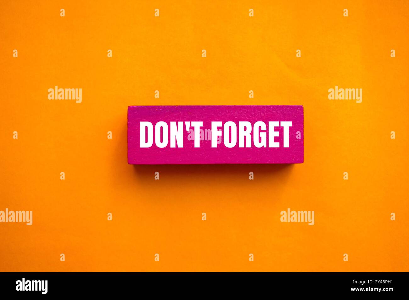 Don't forget message written on pink wooden block with orange ...