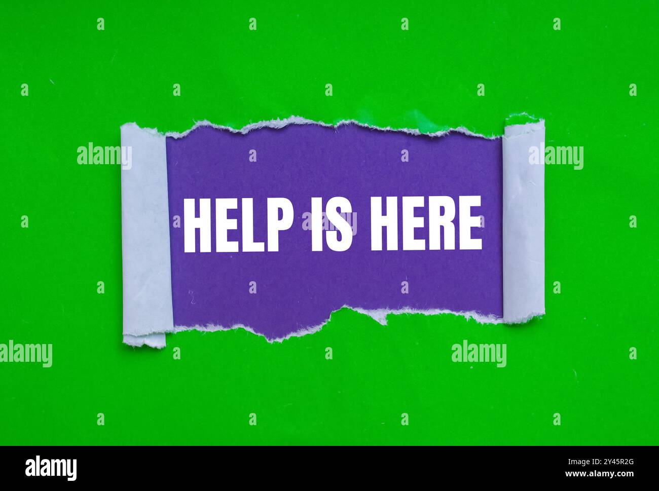 Help is here message written on ripped torn green paper on purple ...