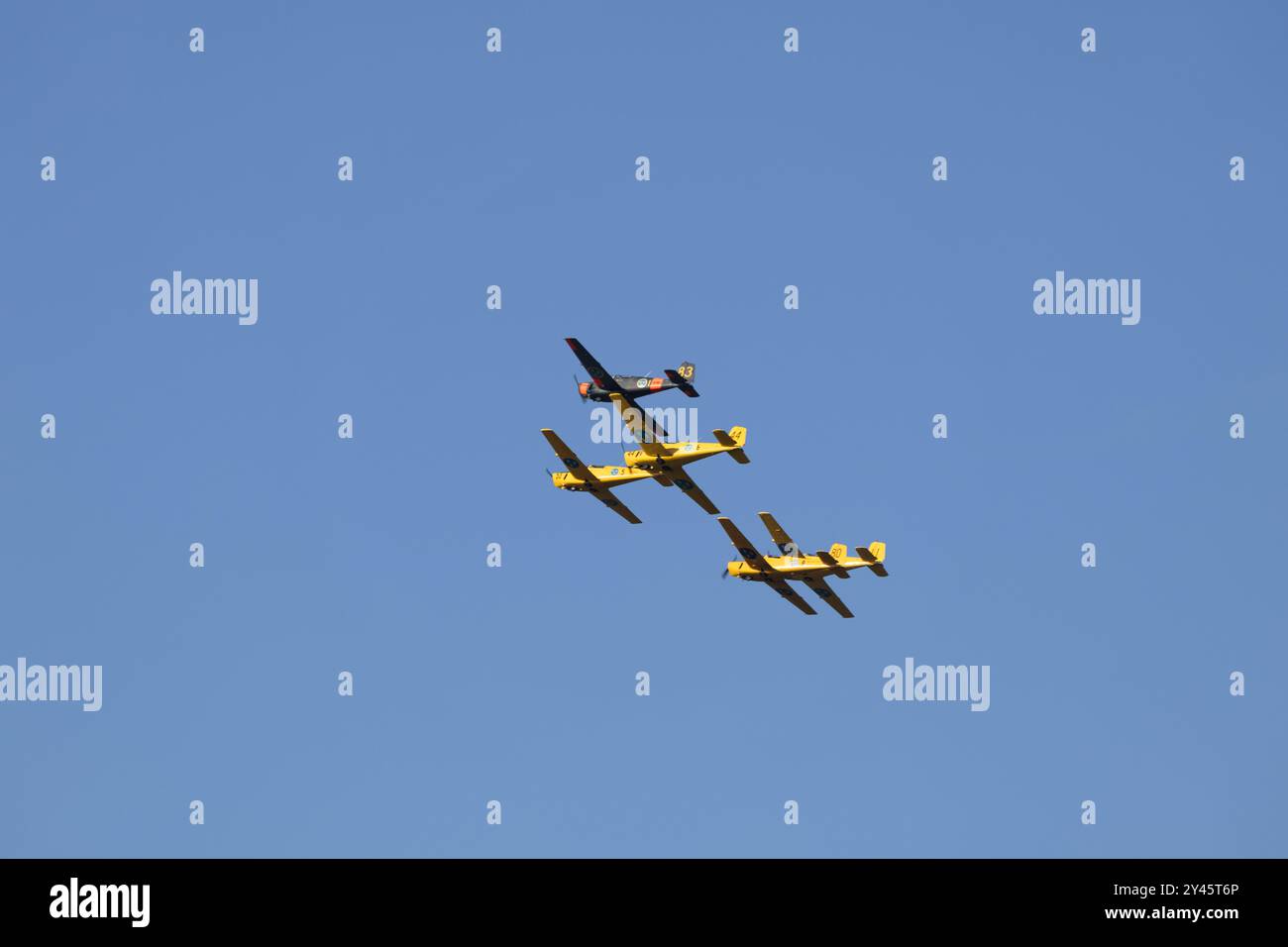 Three small aircraft in formation flying against a clear blue sky ...
