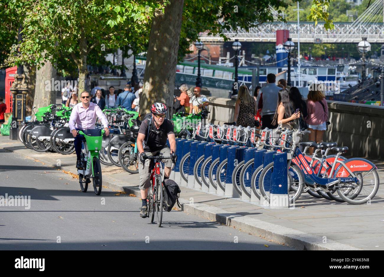 London, UK. Cyclists cycling past rows of rental bikes on the Victoria ...