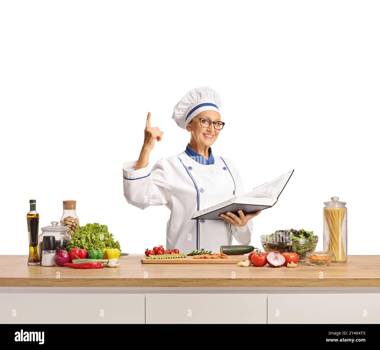 Female chef posing behind a counter with vegetables and holding a cook ...