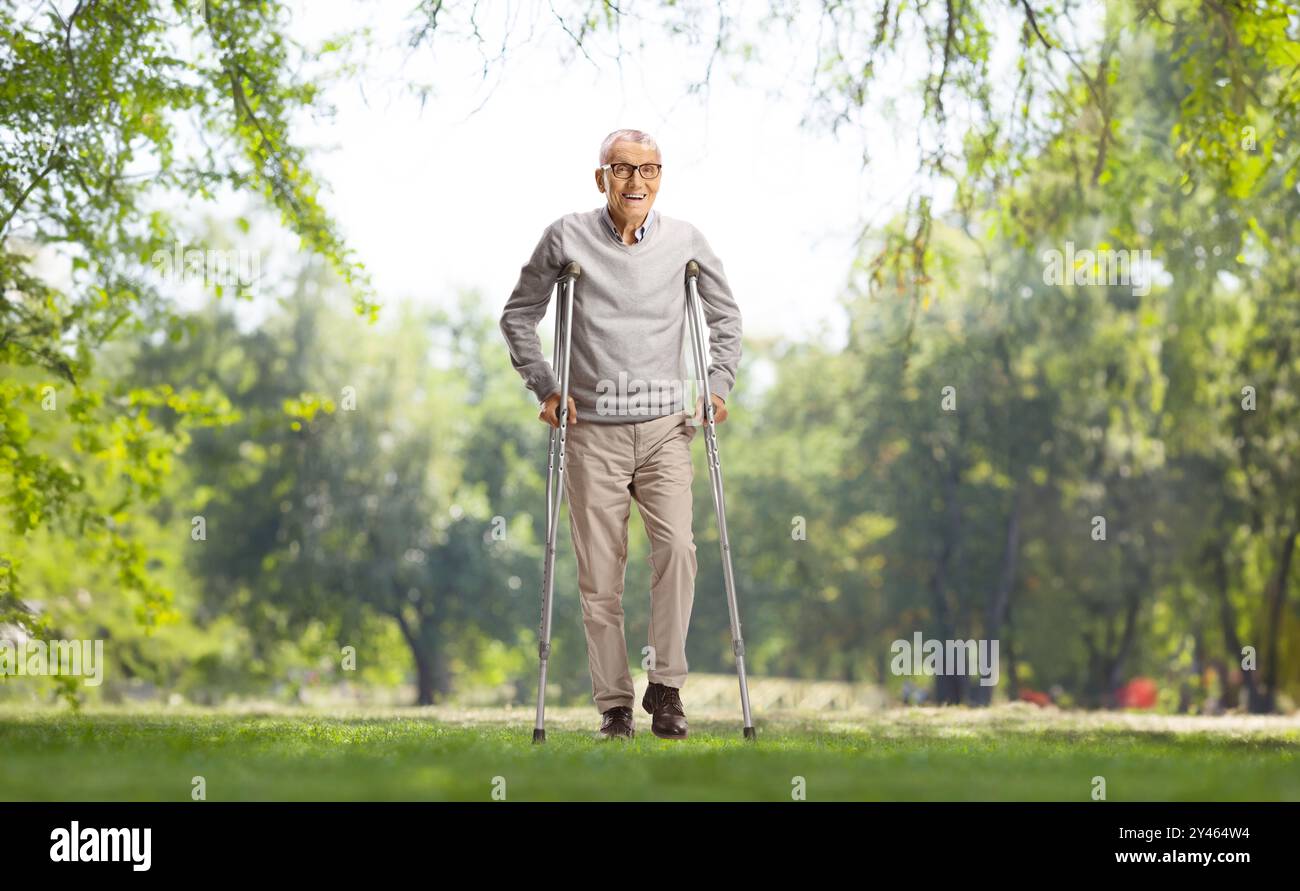 Elderly man with injured leg standing with crutches in a park Stock ...