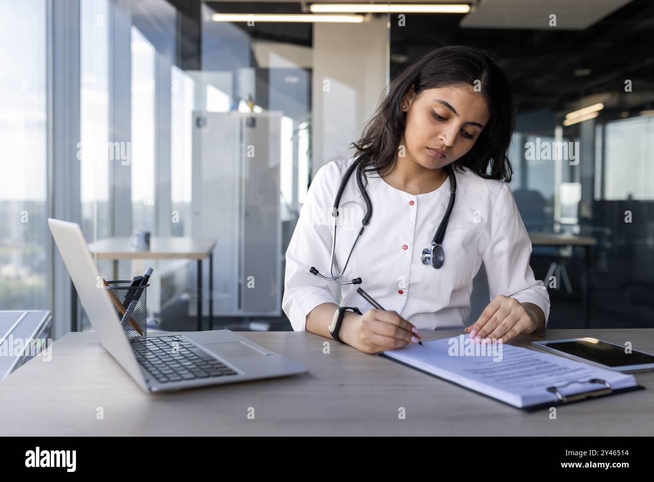 Serious thinking female doctor behind paperwork inside office, female ...