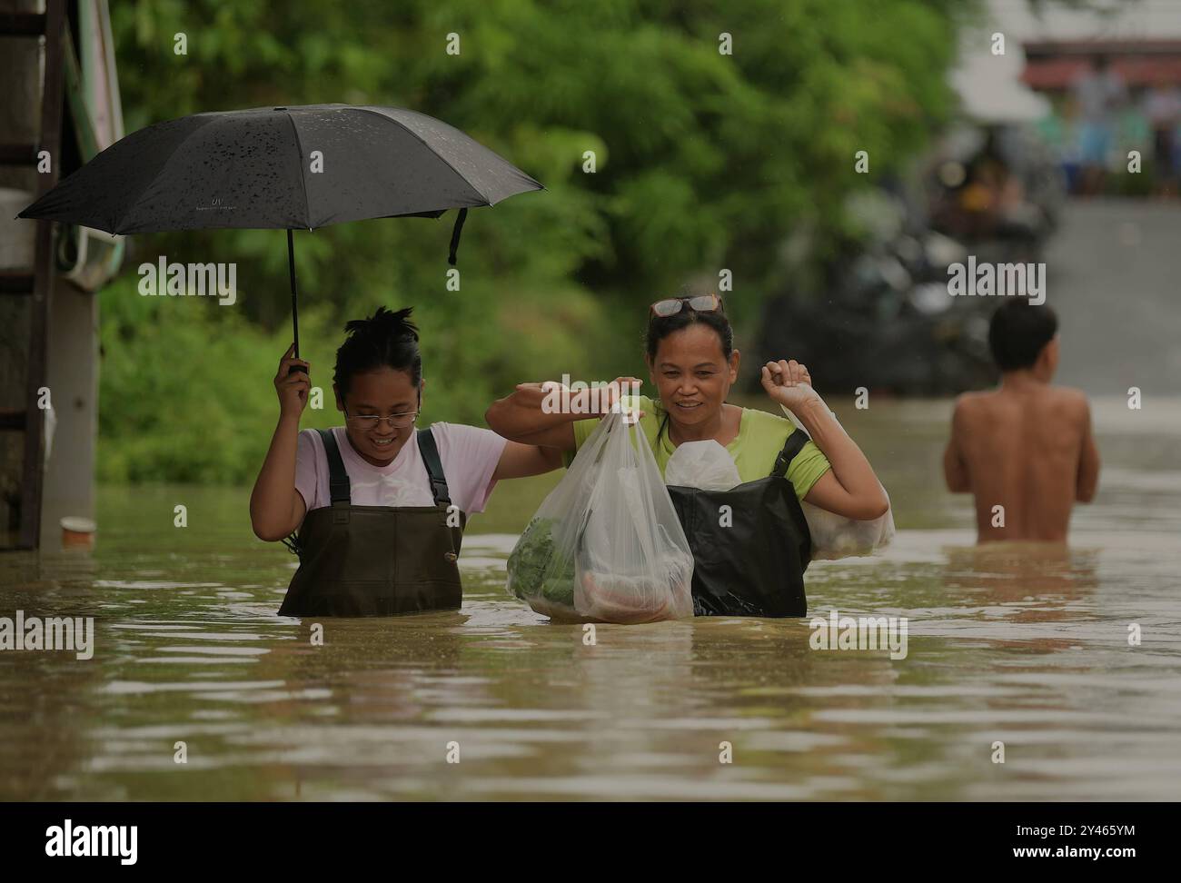 Philippines Typhoon Yagi Women wade along a flooded street caused by ...