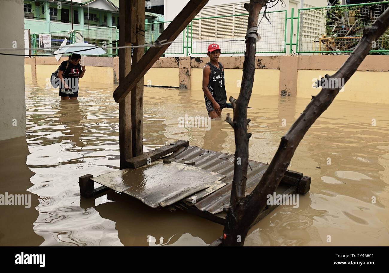 Philippines Typhoon Yagi People wade through a flooded street caused by ...
