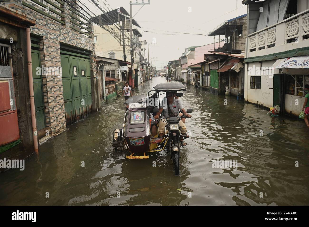 Flooding caused by typhoon Yagi in Philippines A man drives a passenger ...