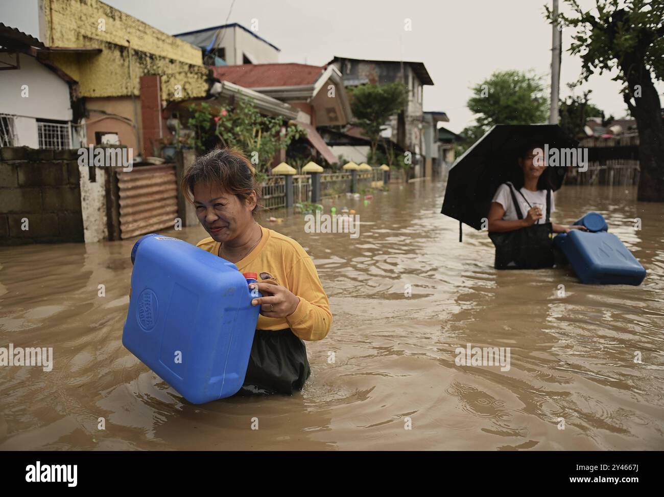 Philippines Typhoon Yagi People wade through a flooded street caused by ...