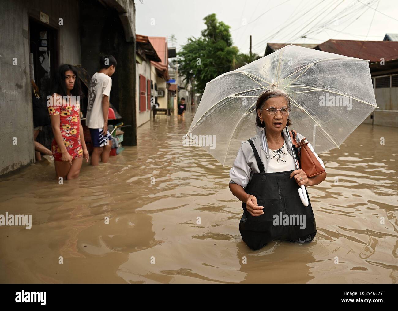 Philippines Typhoon Yagi People wade through a flooded street caused by ...