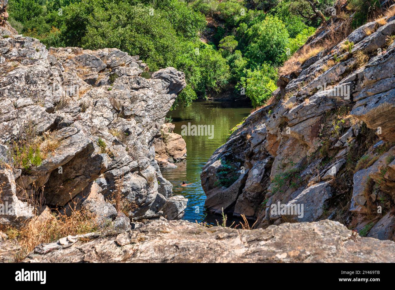 Narrow rocky gorge with still green water at Pego das Pias, a hidden ...