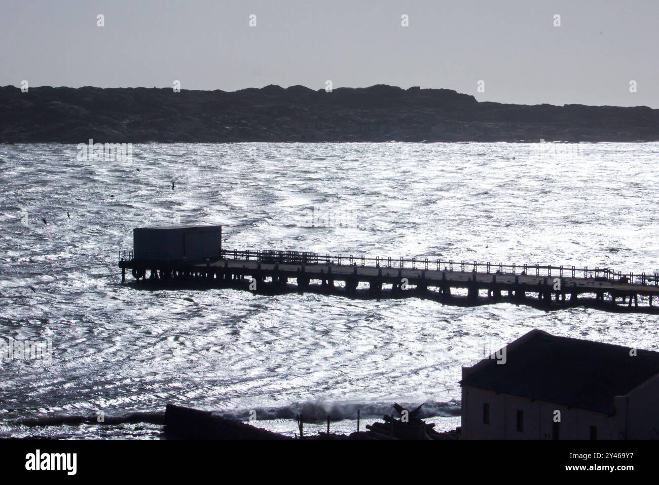 Silhouette of a long fishing pier extending into the bay at one of the ...