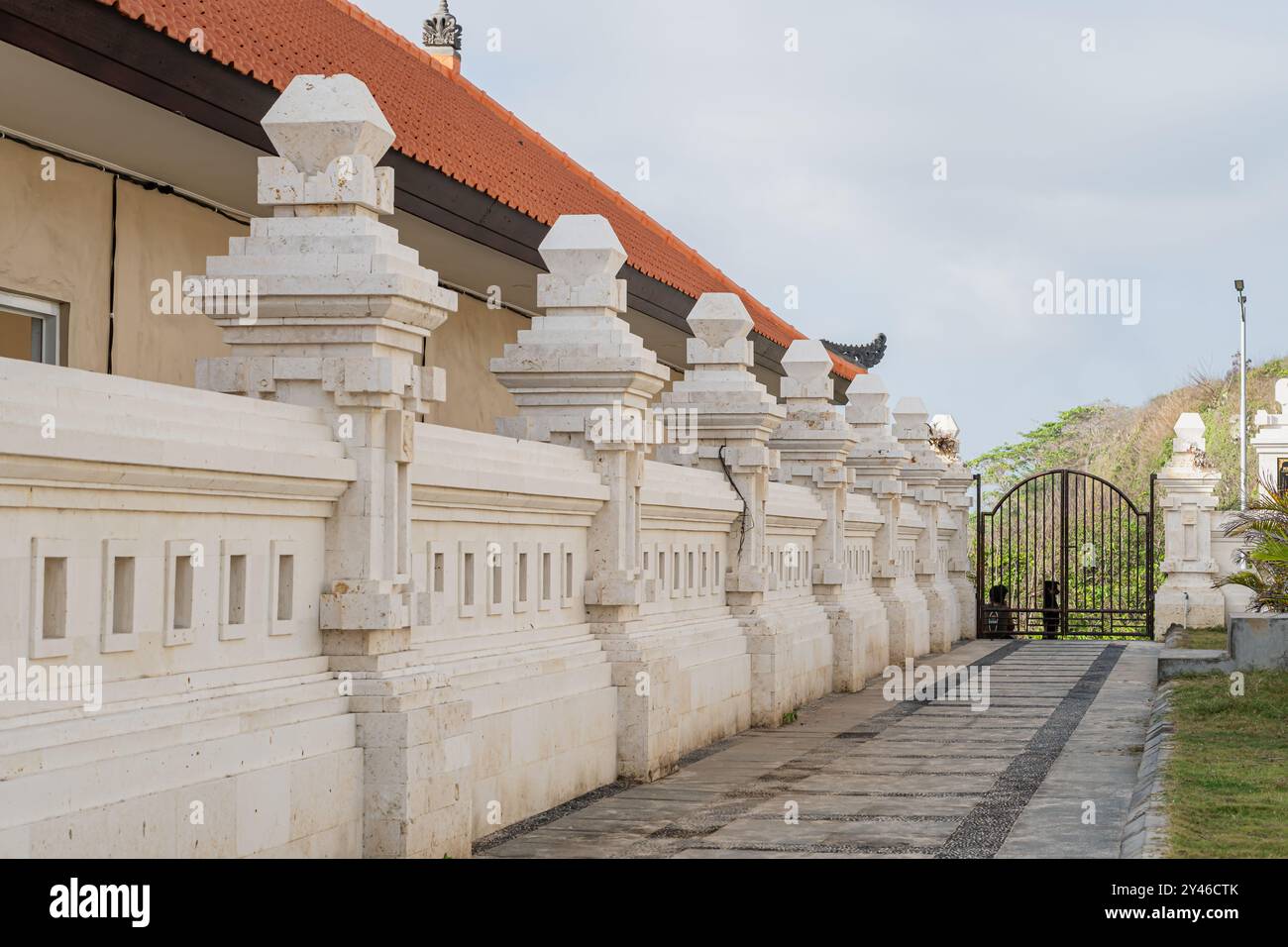 A stone wall with decorative pillars and a gate, leading to a pathway ...