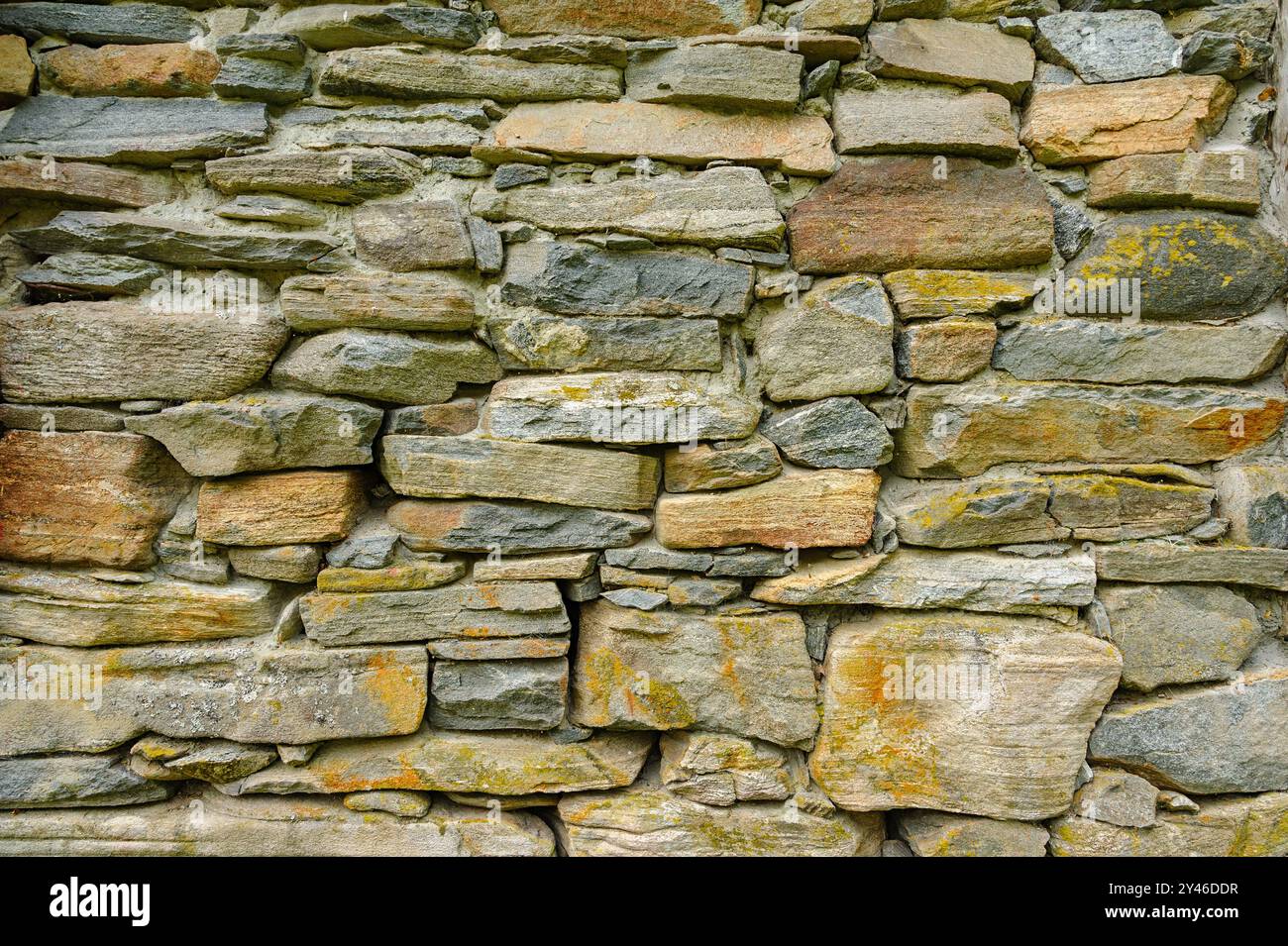 A close-up view of a rugged stone wall showcases an array of colors and ...