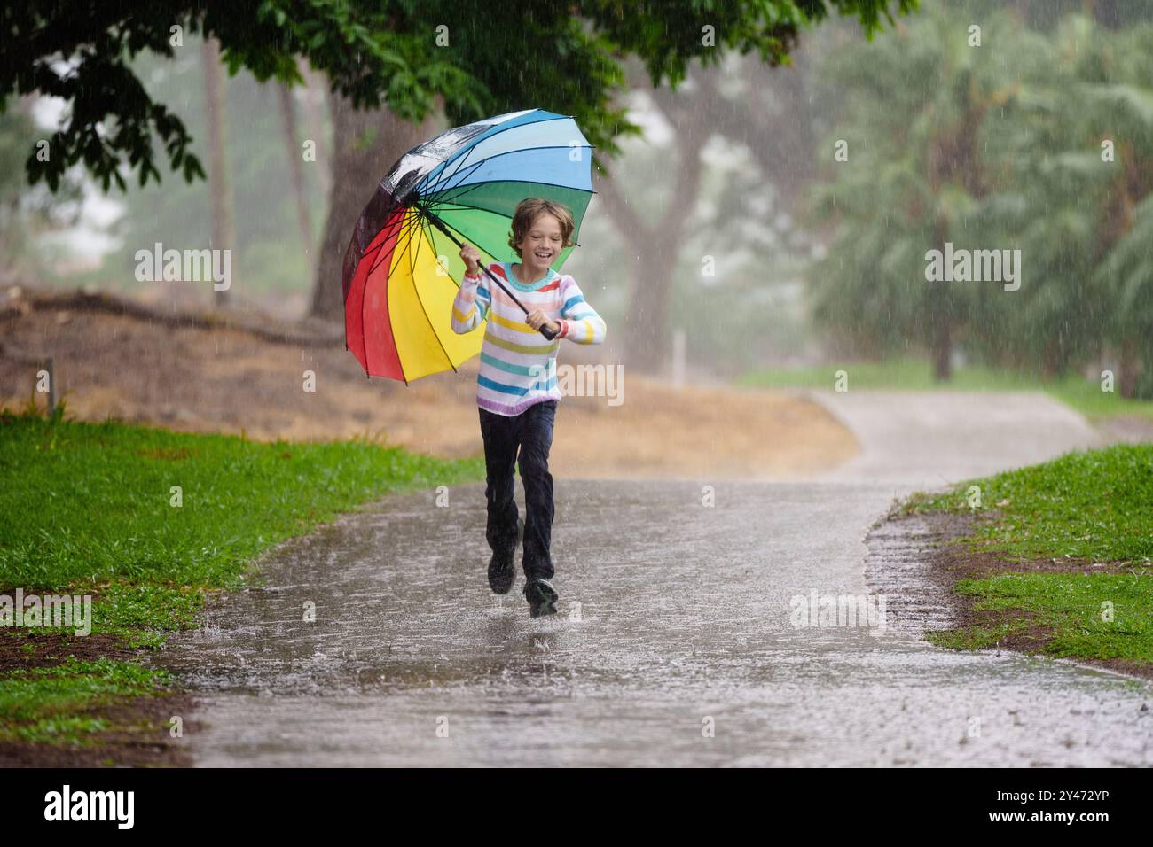 Child playing in autumn rain. Kid jumping in muddy puddle in beautiful ...