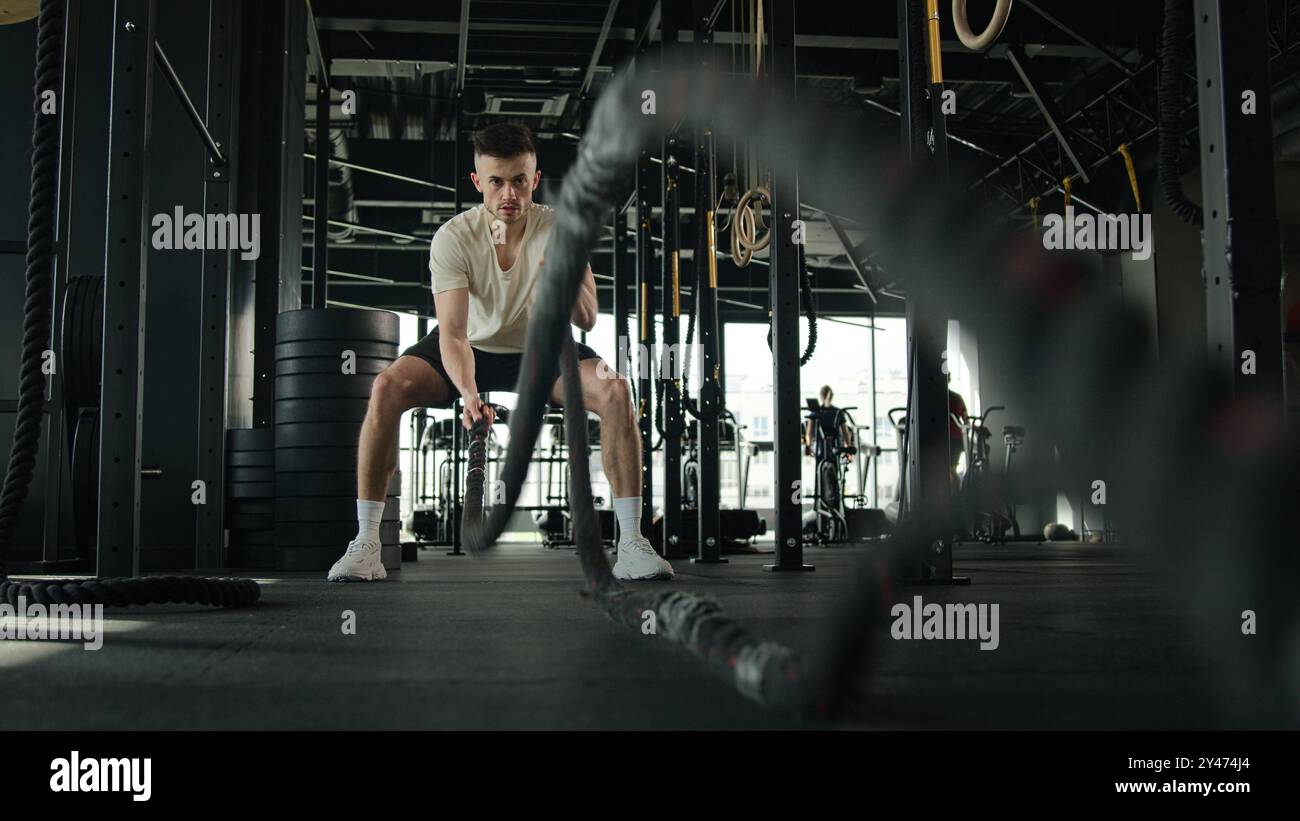 Active man training with battle ropes waves in gym bodybuilding muscle ...