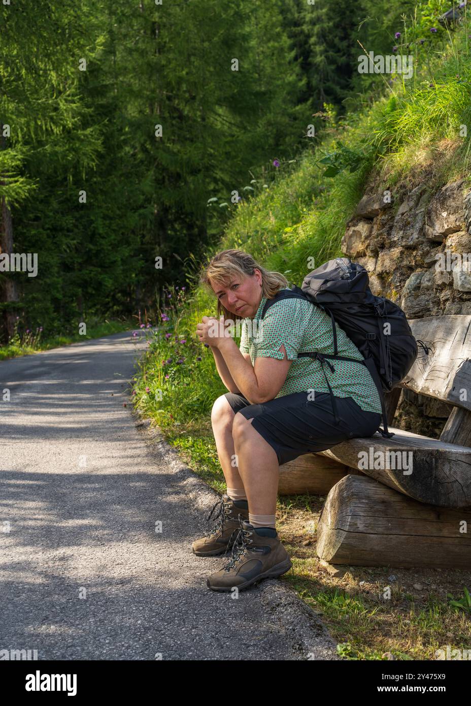 Woman with backpack is very tired on hike. She rests little and goes on ...