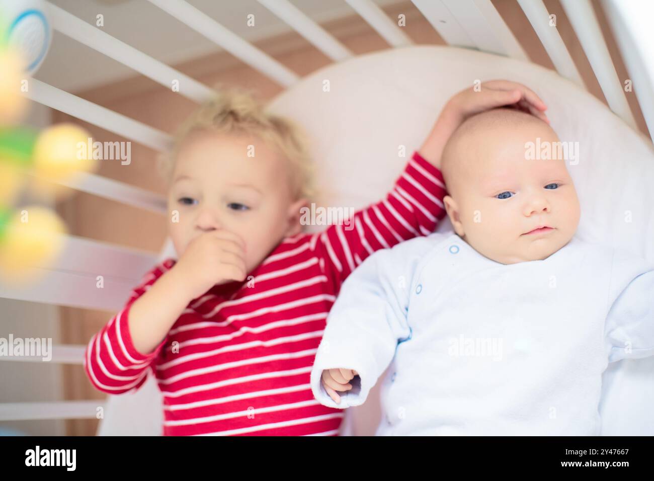Child watching newborn baby in bassinet. Sibling meeting new family ...