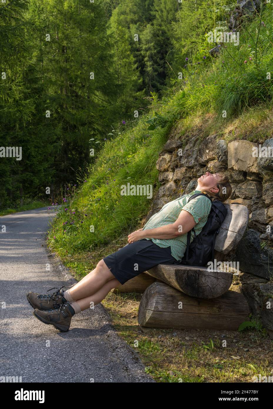 Tired middle aged woman with backpack leaned back on bench and closed ...