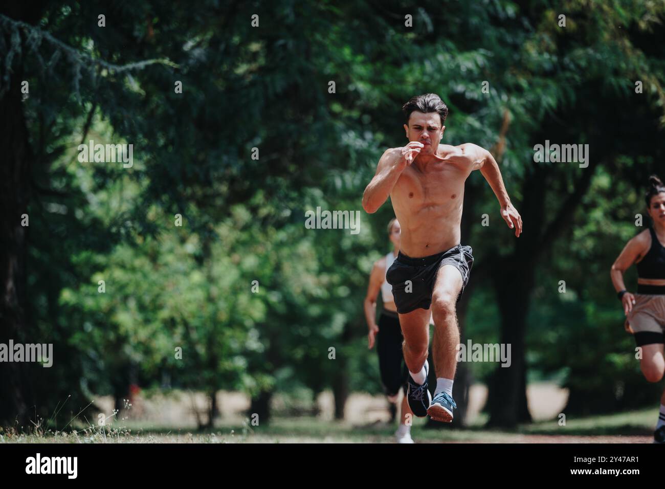 Group of athletes sprinting in a park, engaging in outdoor fitness and ...