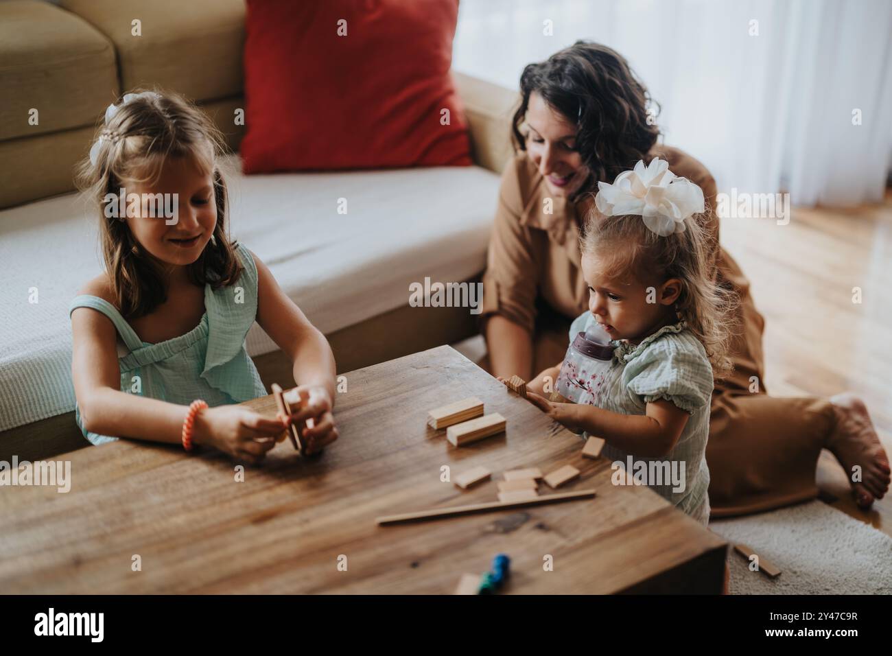 Happy mom playing with daughters at home with wooden blocks Stock Photo - Alamy