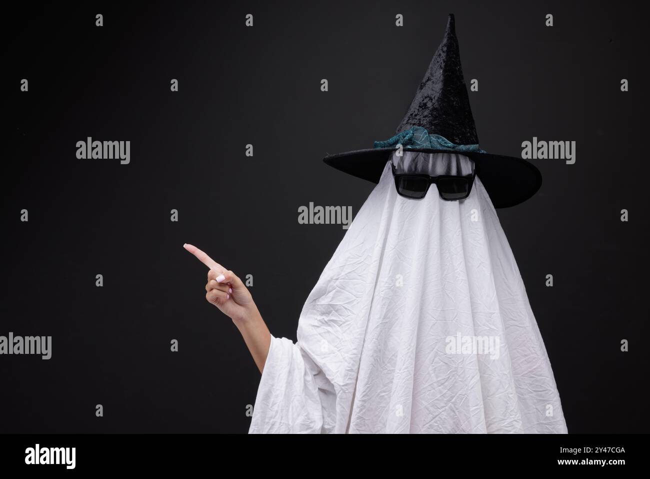 Person in costume of ghost pointing at something on dark background ...
