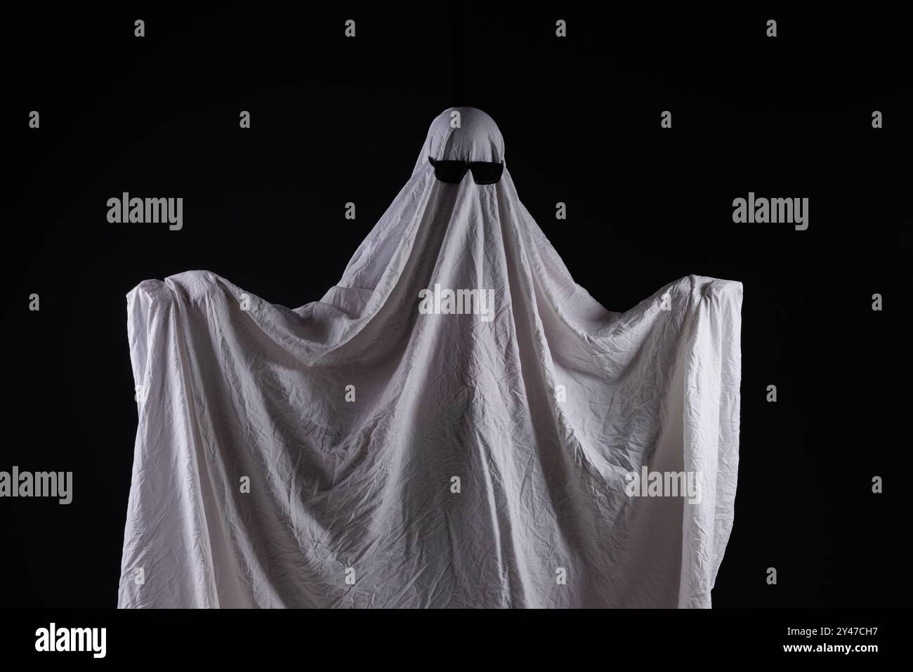 Person in costume of ghost pointing at something on dark background ...