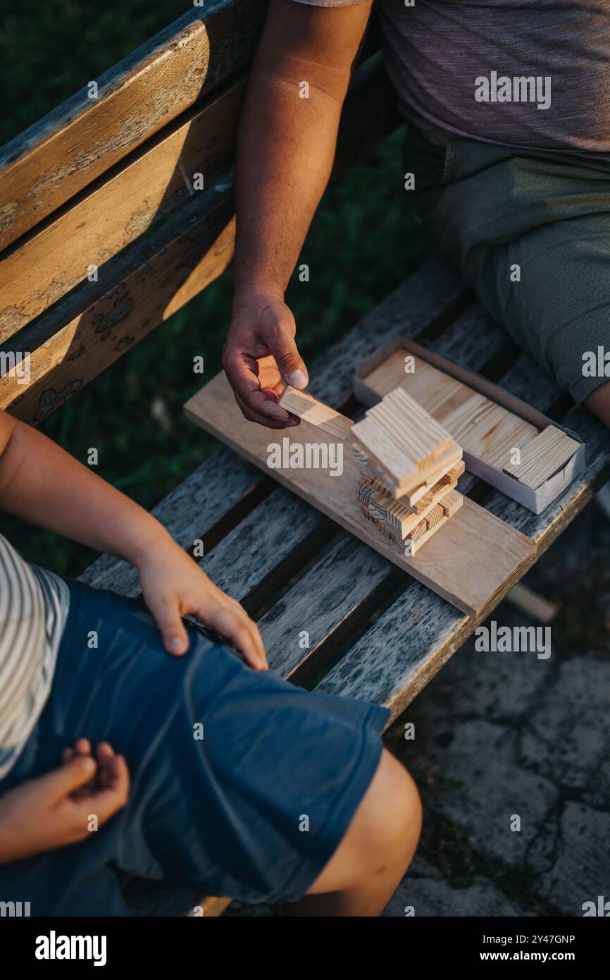 Father and son playing building blocks game on park bench Stock Photo ...