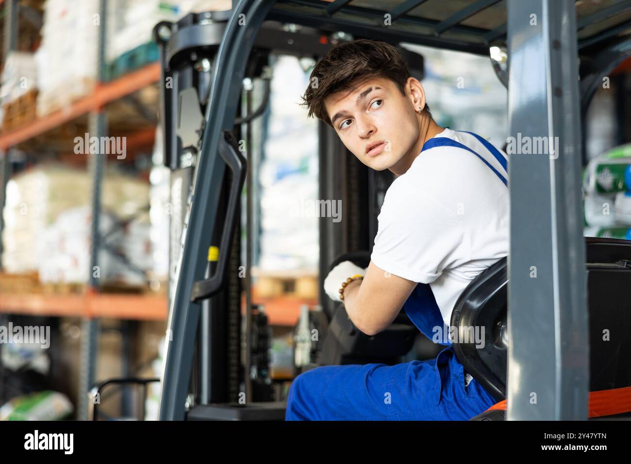 Young guy worker works on loader in warehouse Stock Photo - Alamy