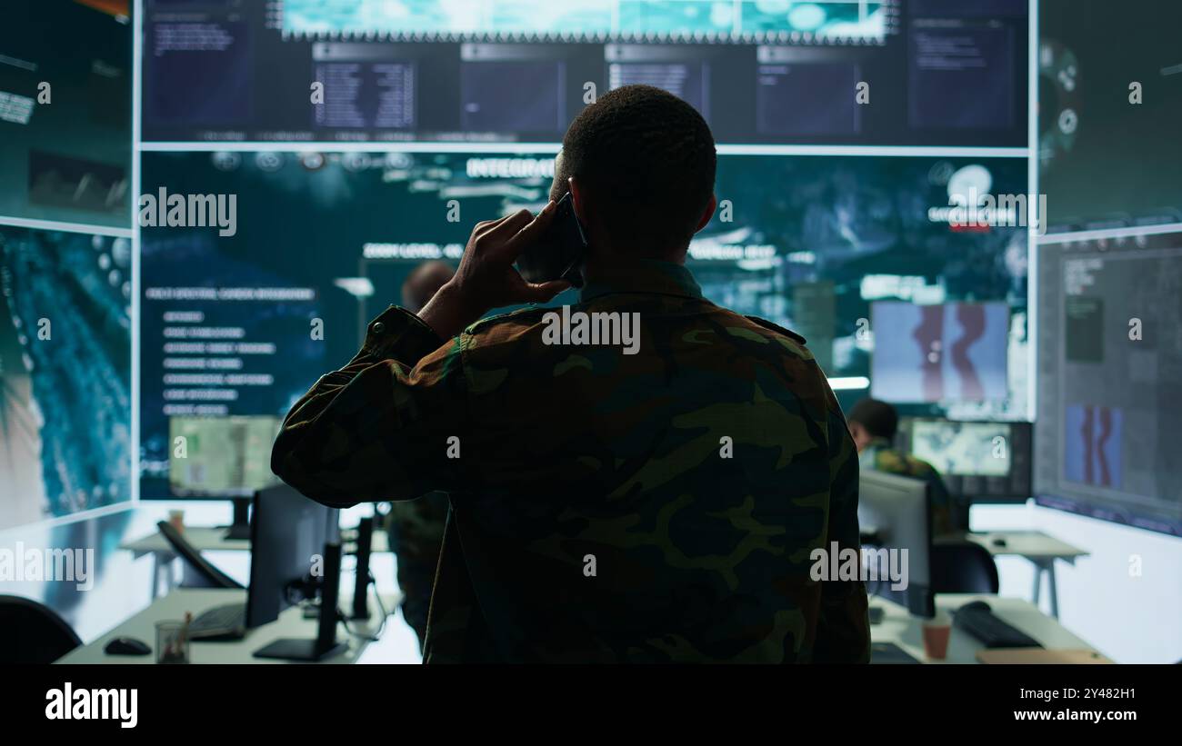 Military man answers phone call in a mission control center, working ...