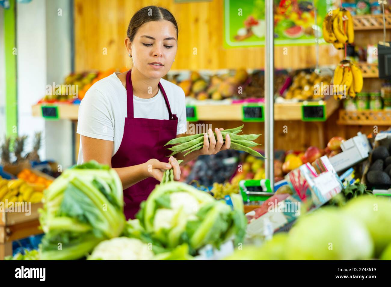Grocery store female employee in an apron puts beans on shelves Stock ...