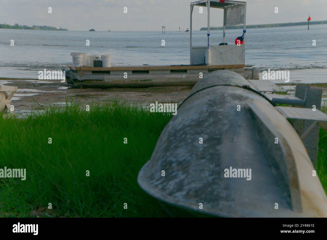 Wide angle view out over metal pontoon tube washed up on shore in green ...