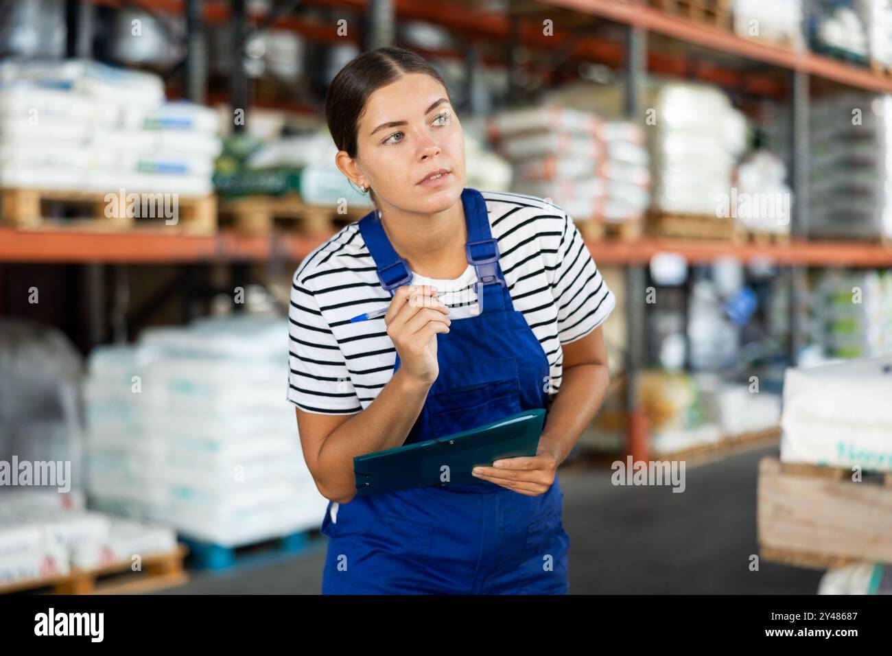 In warehouse of store, girl checks quantity of goods and receipt ...
