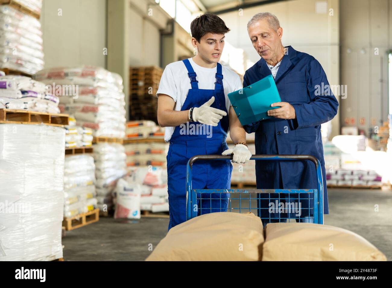 Elderly man and young guy check documents in warehouse Stock Photo - Alamy