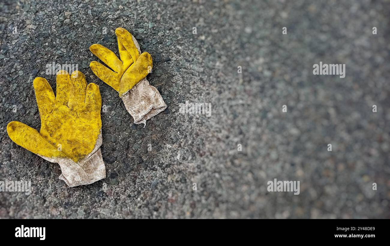 Used yellow work gloves on asphalt road Stock Photo - Alamy