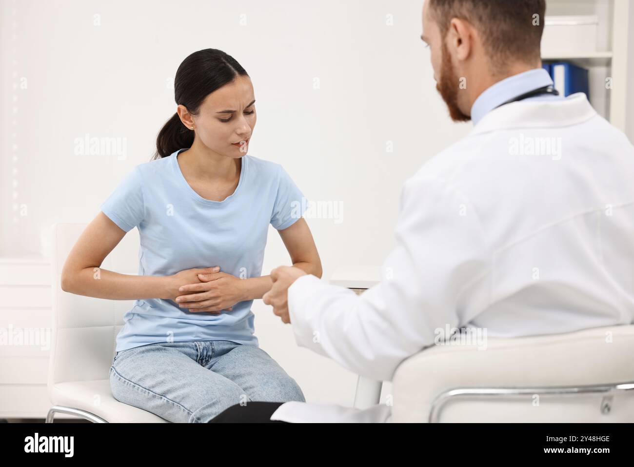Doctor consulting patient with stomach pain in clinic Stock Photo - Alamy