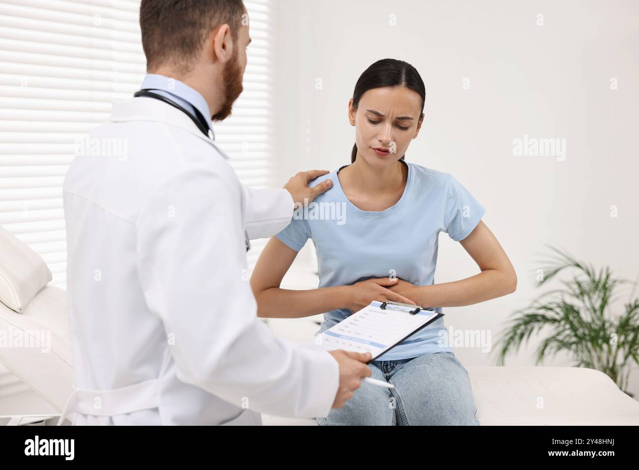 Doctor consulting patient with stomach pain in clinic Stock Photo - Alamy