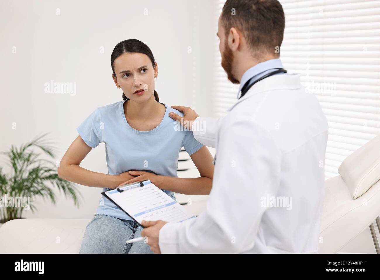 Doctor consulting patient with stomach pain in clinic Stock Photo - Alamy